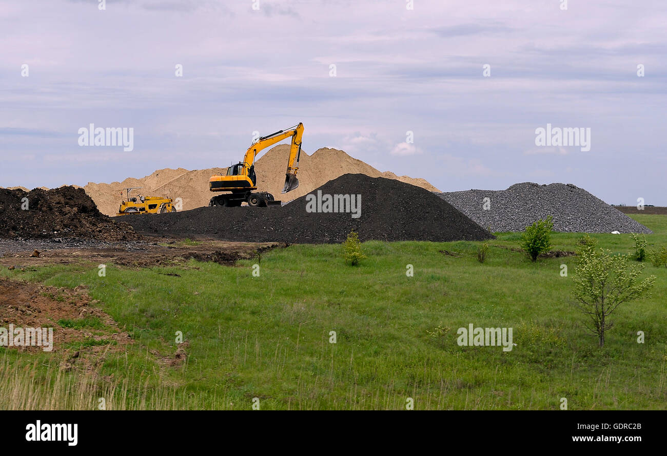 Yellow excavator working digging in sand quarry Stock Photo - Alamy