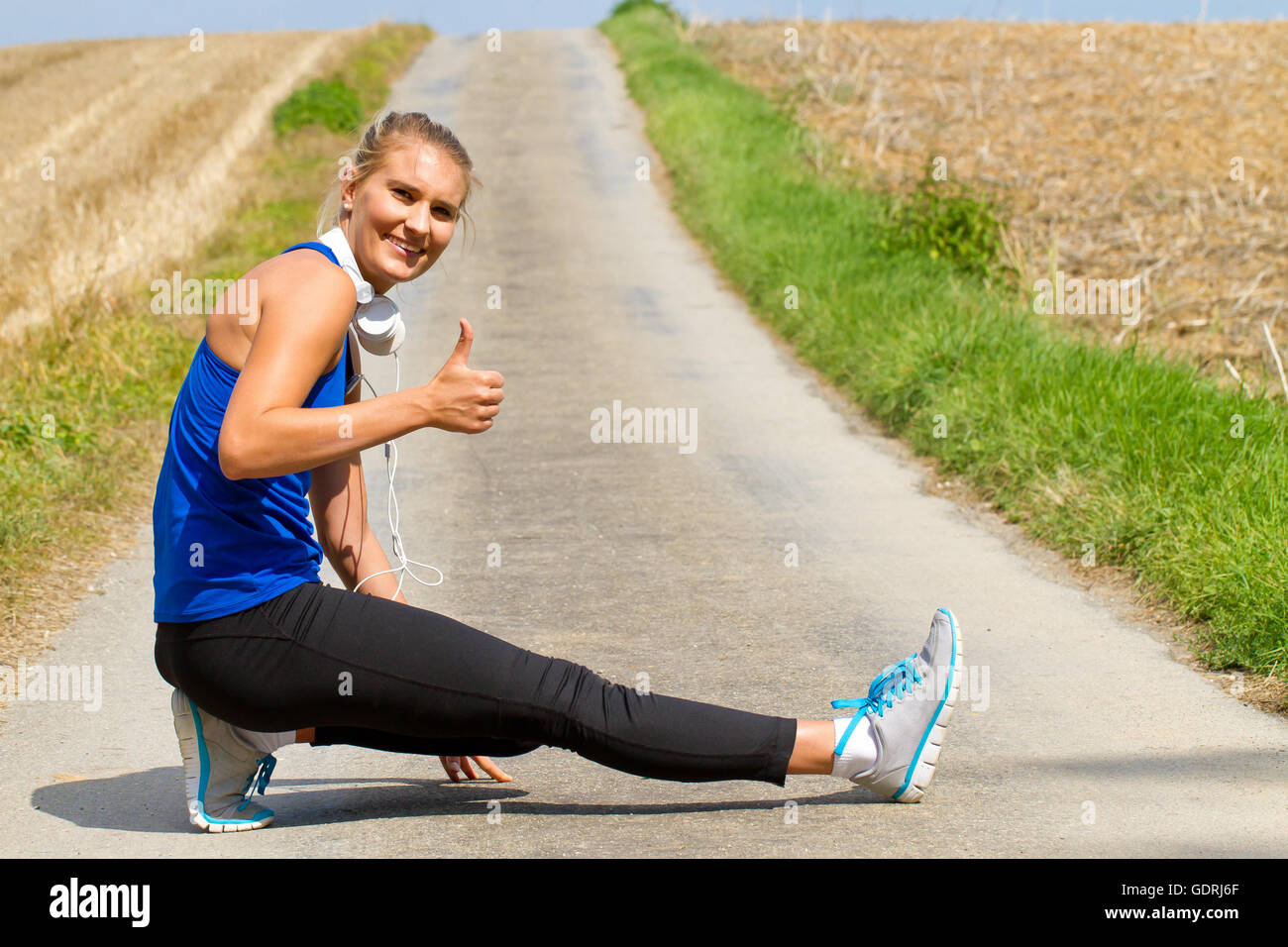 Young woman stretching before jogging Stock Photo - Alamy
