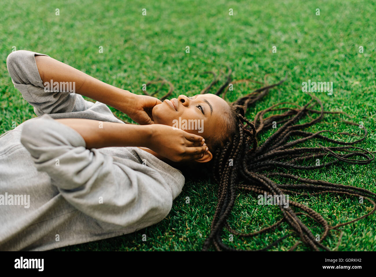 Close-up portrait from above of a smiling african woman lying on grass ...