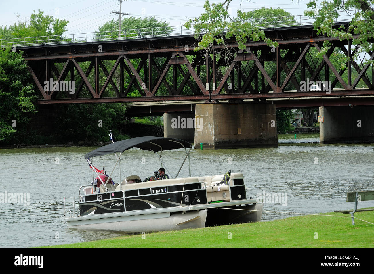 Pontoon Boat moored on shoreline next to train trestle Stock Photo - Alamy