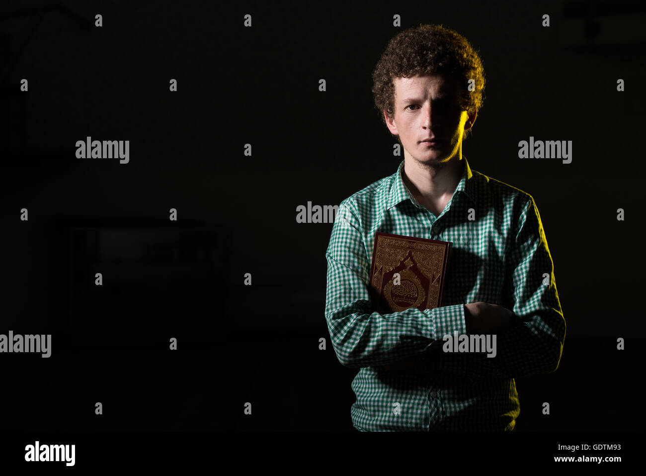 White Muslim Man With Afro Lock Hair Curly Is Holding The Koran In Dark ...