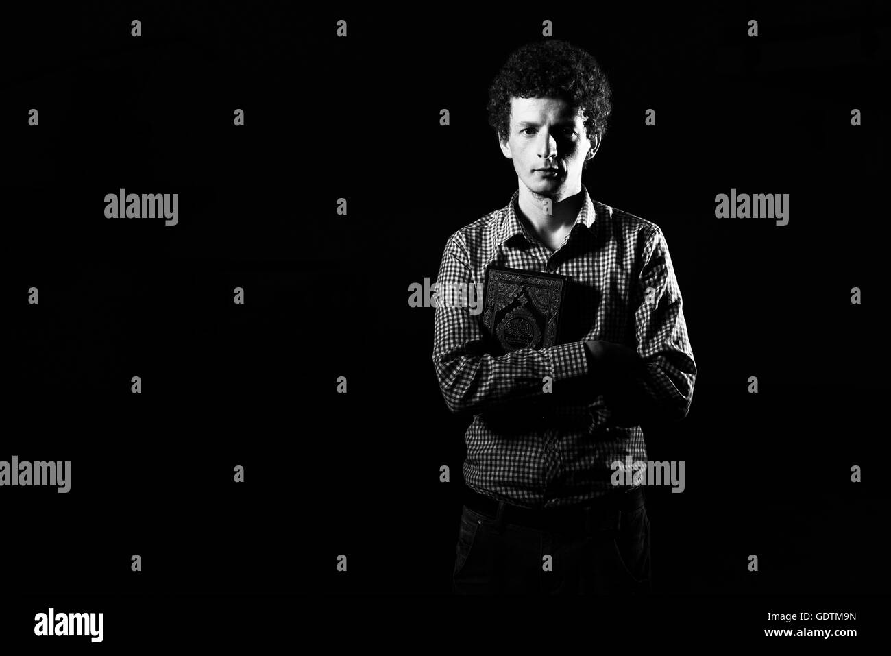 White Muslim Man With Afro Lock Hair Curly Is Holding The Koran In Dark ...