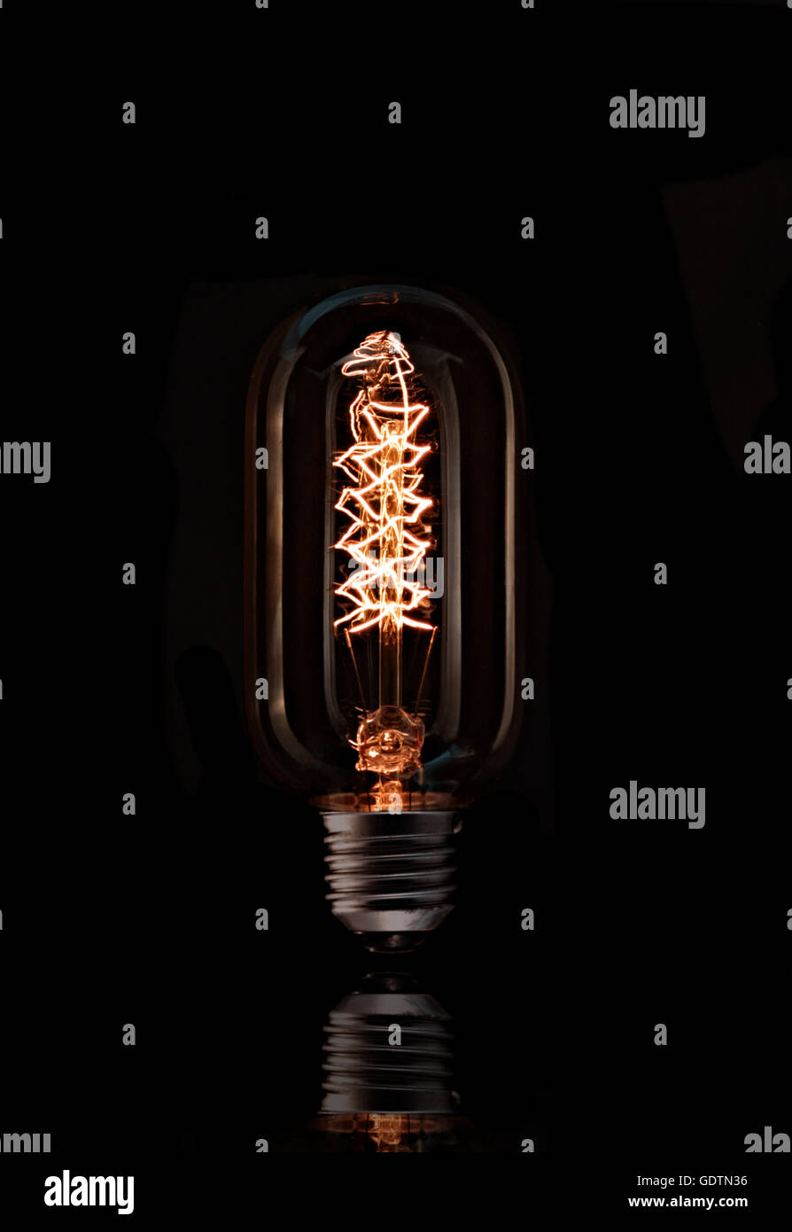 Tall glowing light bulb with angular filament Stock Photo - Alamy