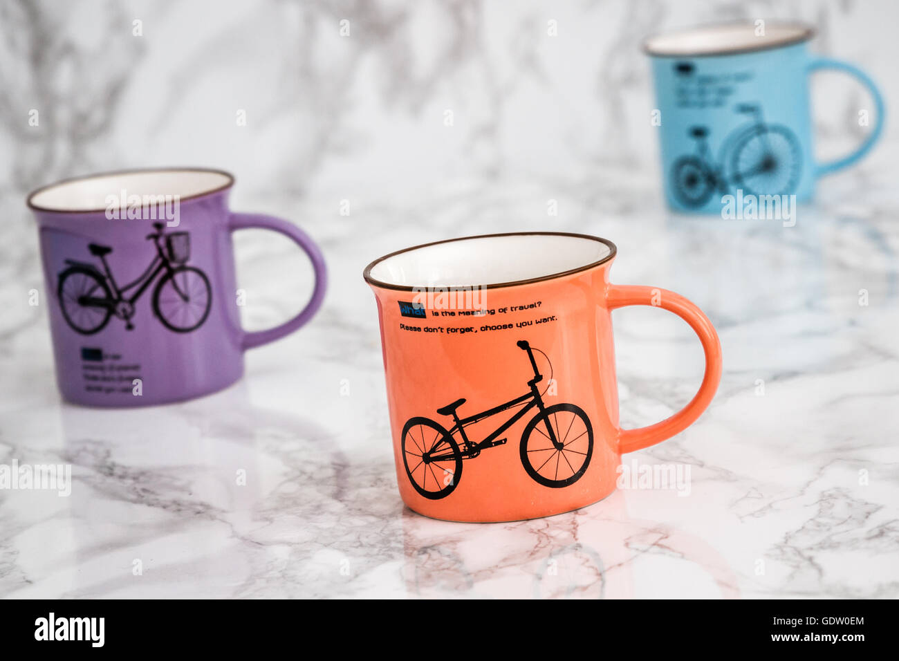 Colorful modern ceramic mugs with bicycle design on white marble ...