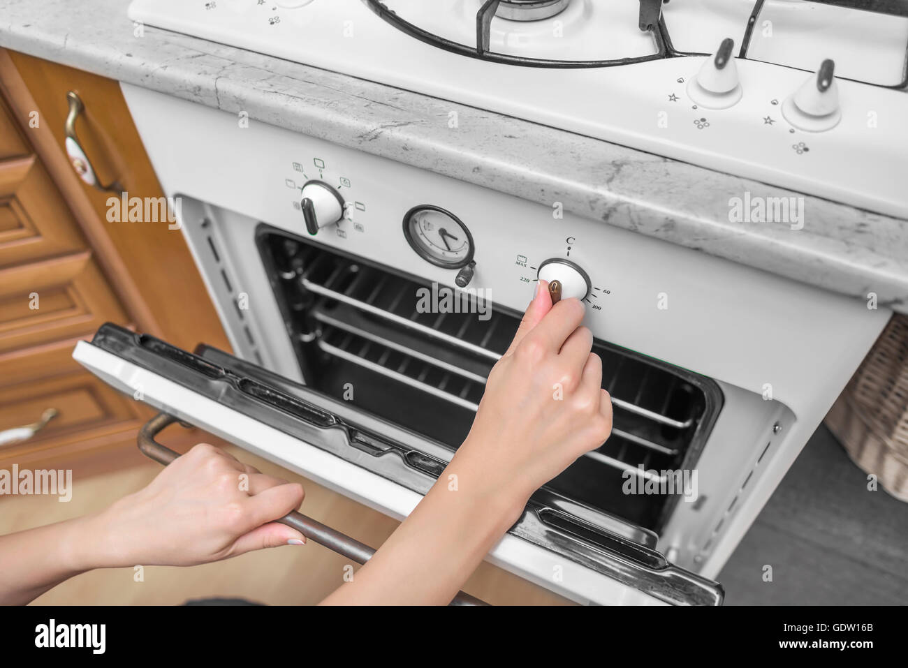 Female hand includes oven in the kitchen. Close-up Stock Photo - Alamy