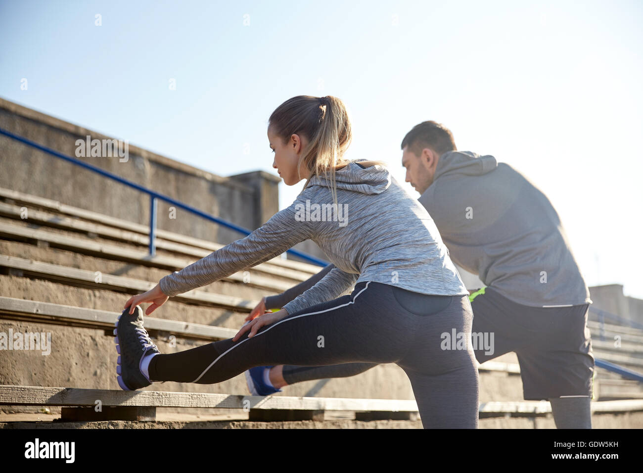 couple stretching leg on stands of stadium Stock Photo - Alamy