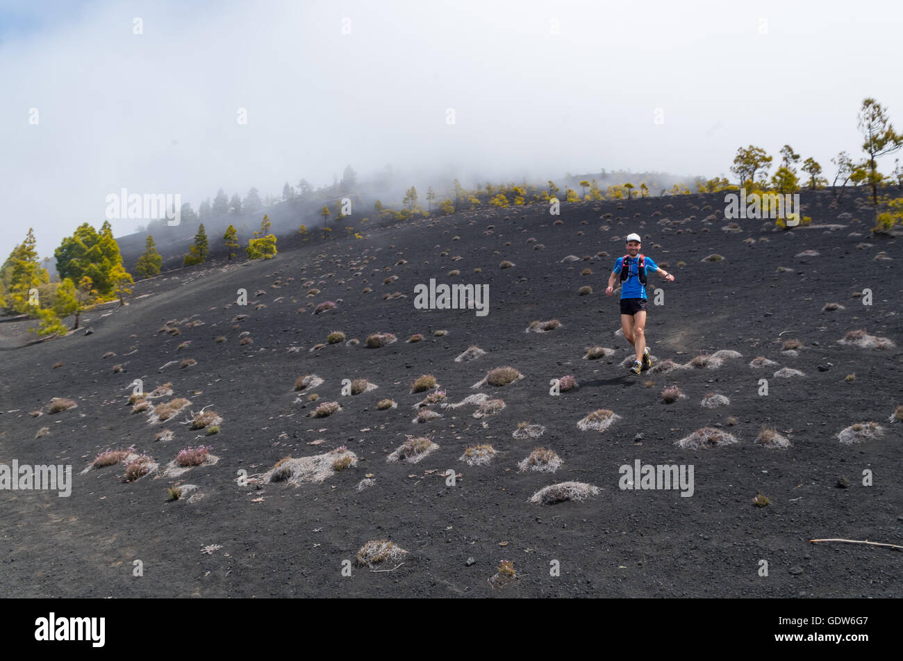 Young man running in volcanic landscape with foggy background, La Palma ...