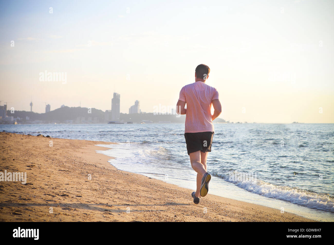 Young man running on the beach at sunset Stock Photo - Alamy