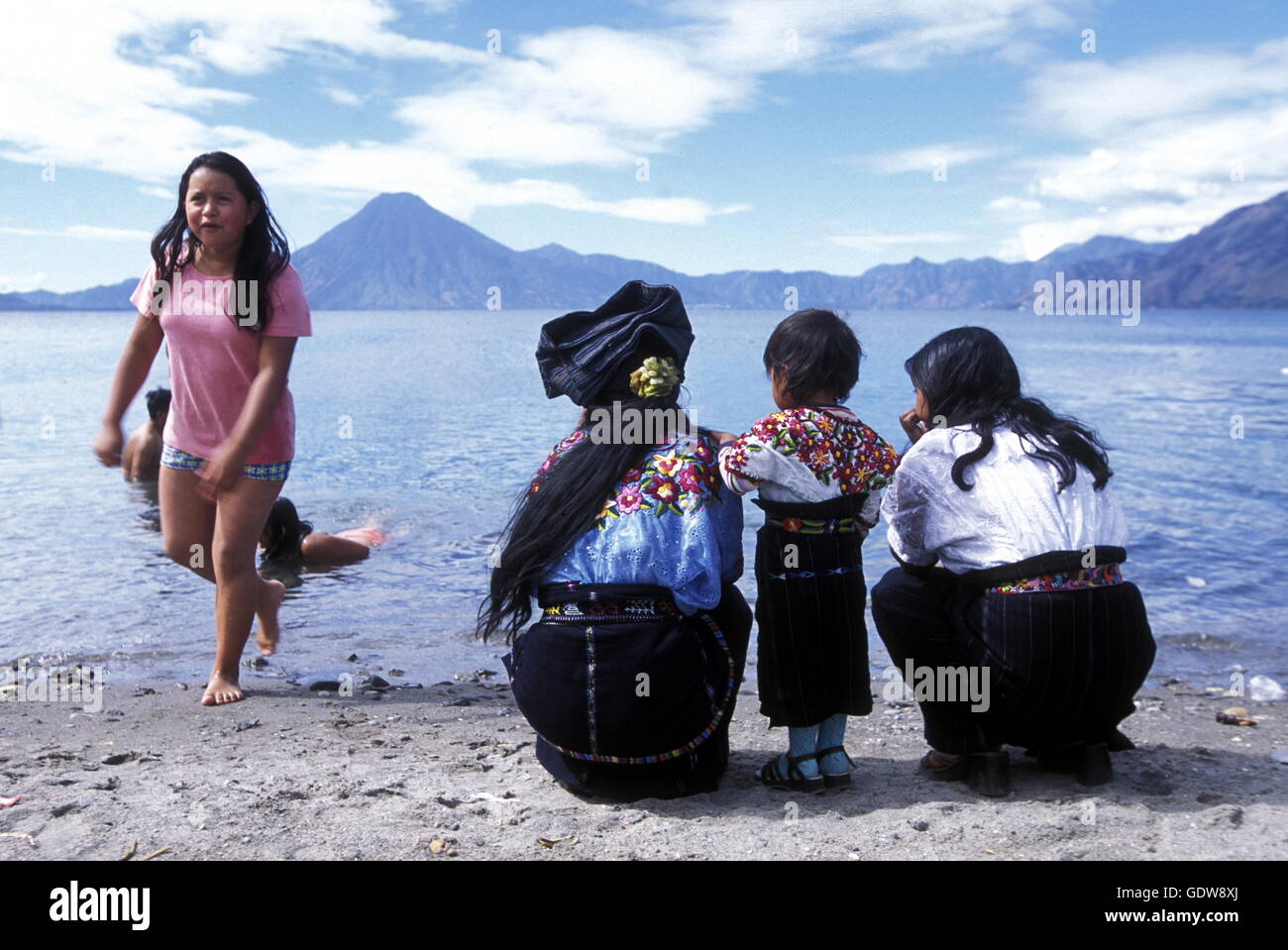 People at the coast of Lake Atitlan mit the Volcanos of Toliman and San ...