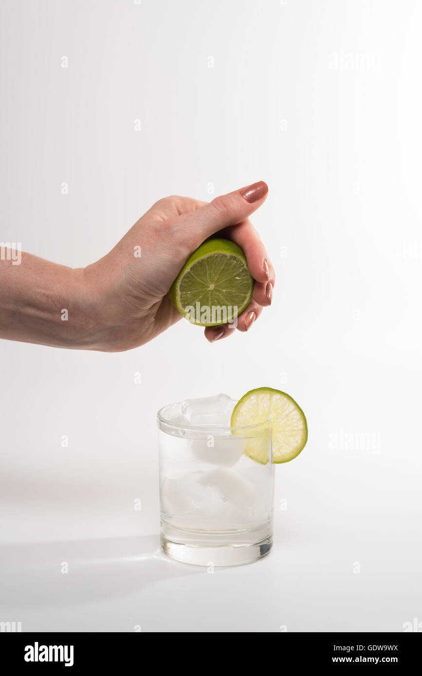 Female hand squeezing lime into glass cocktail Stock Photo - Alamy