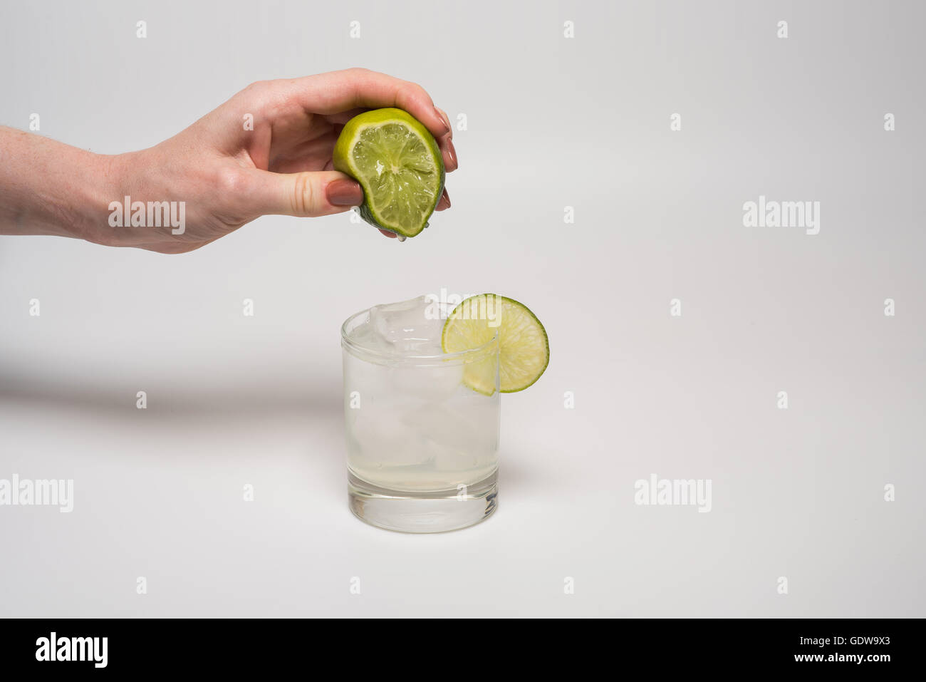 Female hand squeezing lime into glass cocktail Stock Photo - Alamy