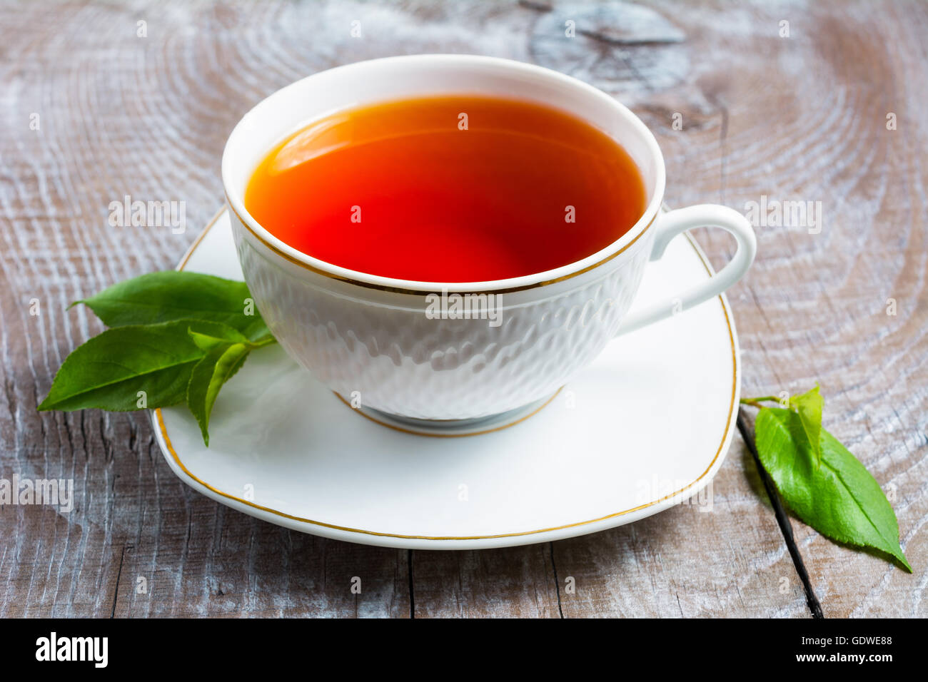 Cup of tea with green leaves on rustic wooden table. Breakfast tea cup ...