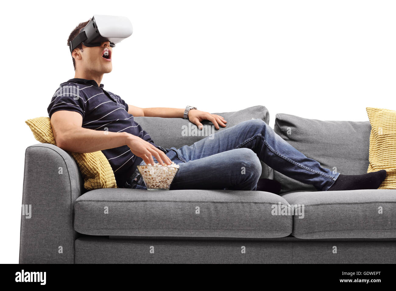 Amazed young man looking in VR goggles and eating popcorn seated on a ...