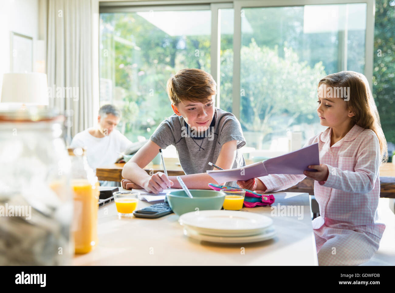 Brother and sister eating breakfast and doing homework Stock Photo - Alamy