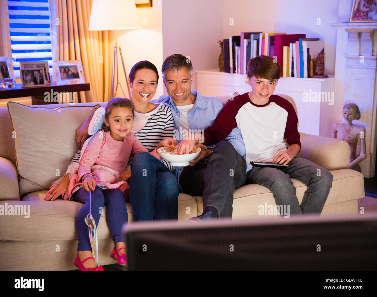 Family eating popcorn and watching TV in living room Stock Photo - Alamy