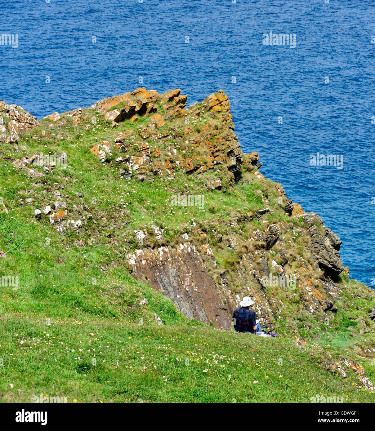 An artist sitting on the edge of cliff sketching the view in Mullion ...