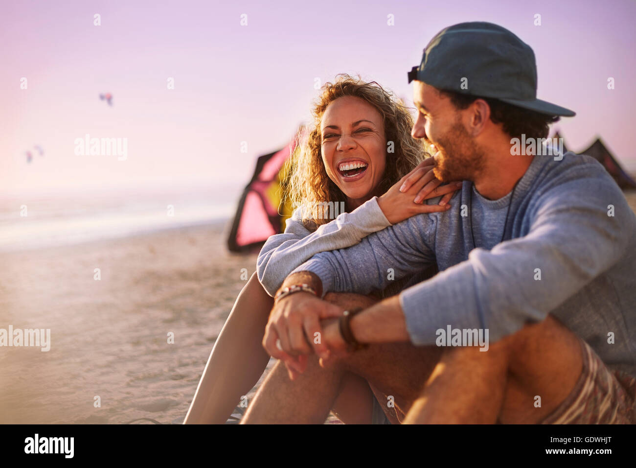 Laughing couple sitting on beach Stock Photo - Alamy