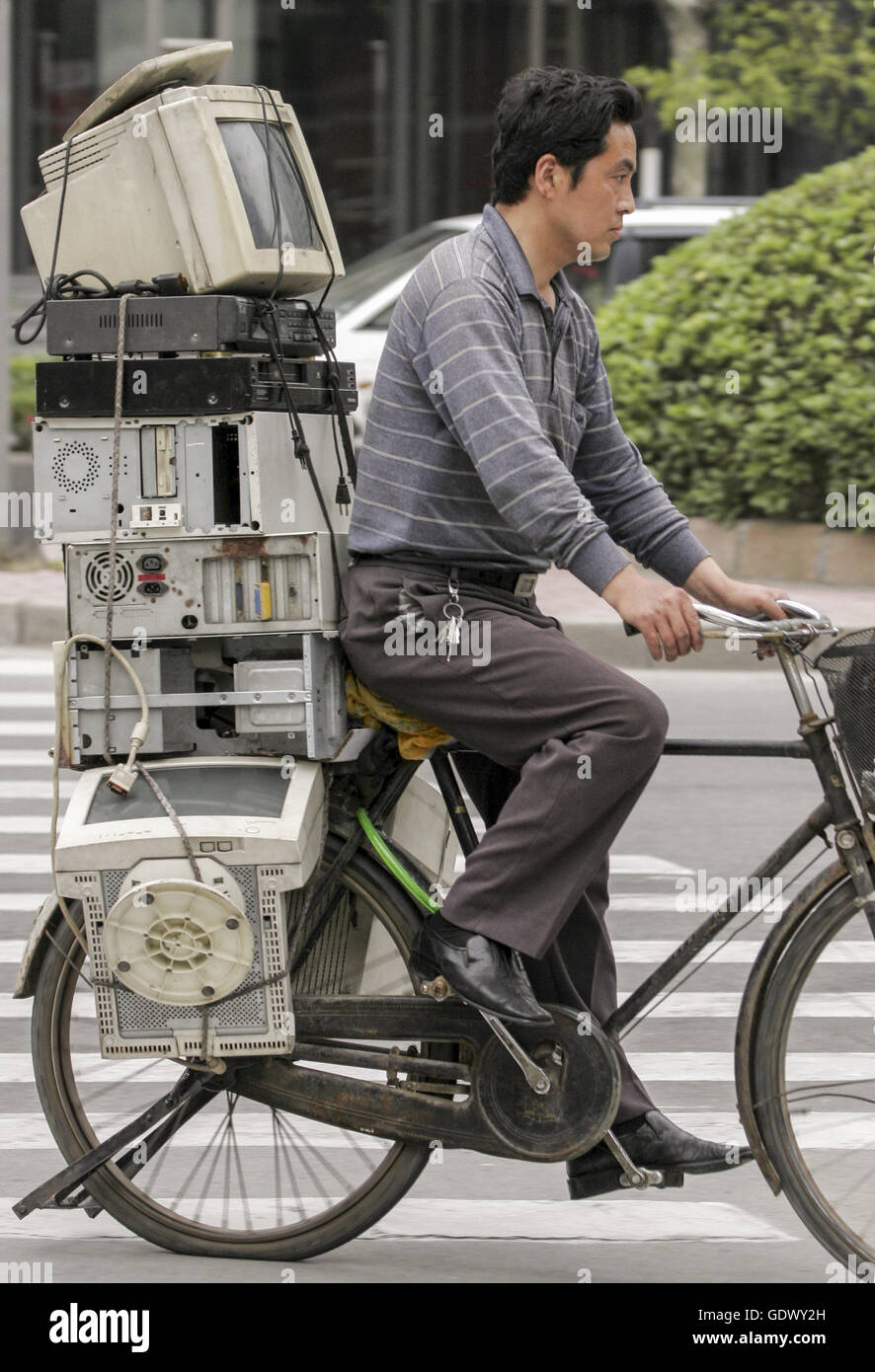 A Chinese peddles his bicycle loaded with old computers on a street of ...