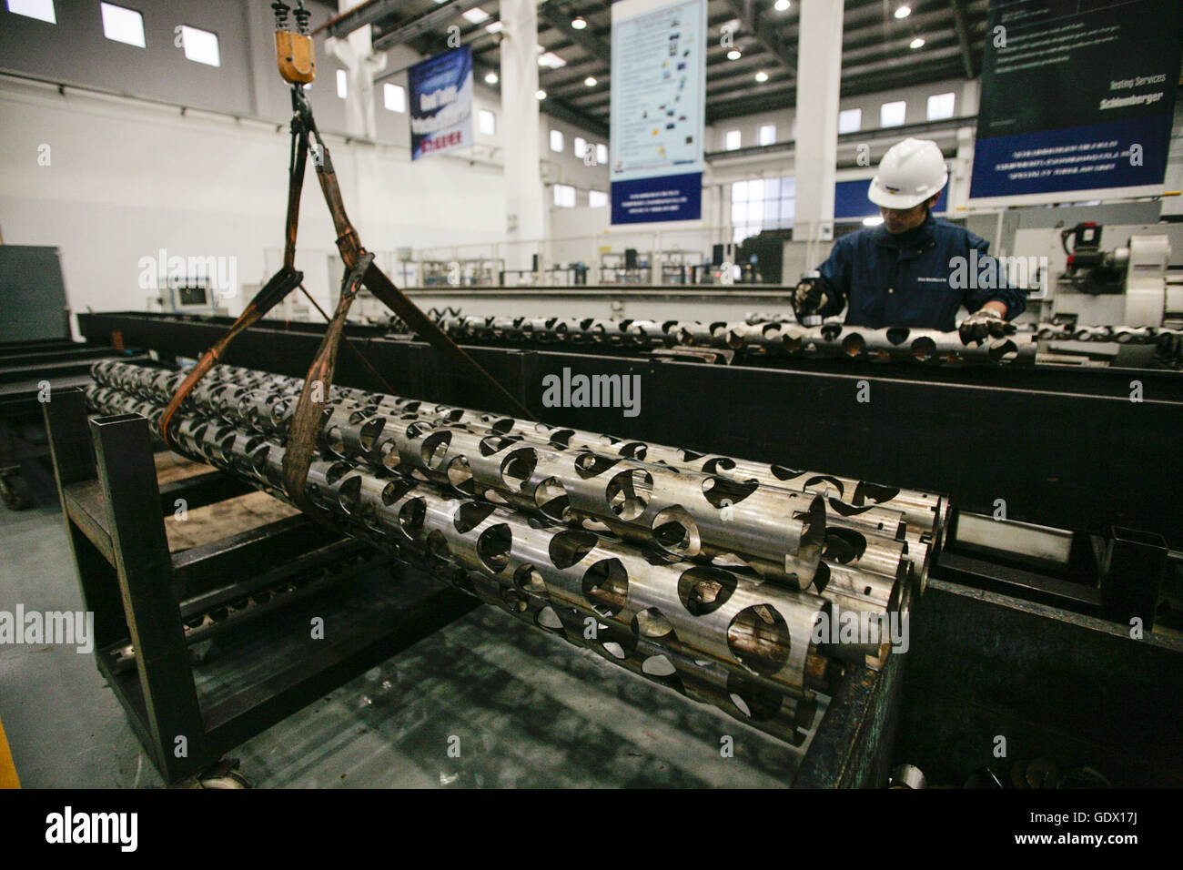 Workers work at a drilling pipe production line in a Schlumberger plant ...