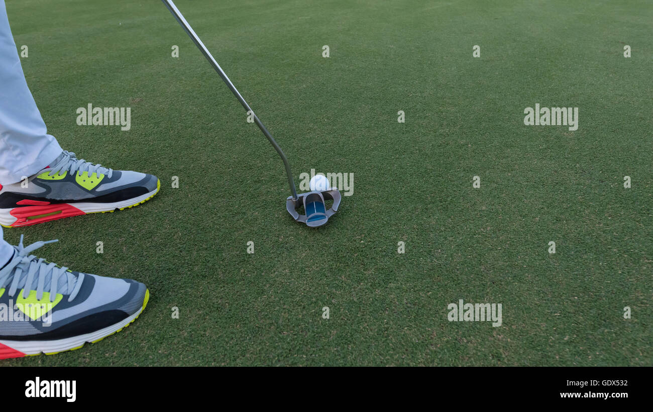 close up of putter hitting golf ball to hole at course Stock Photo - Alamy