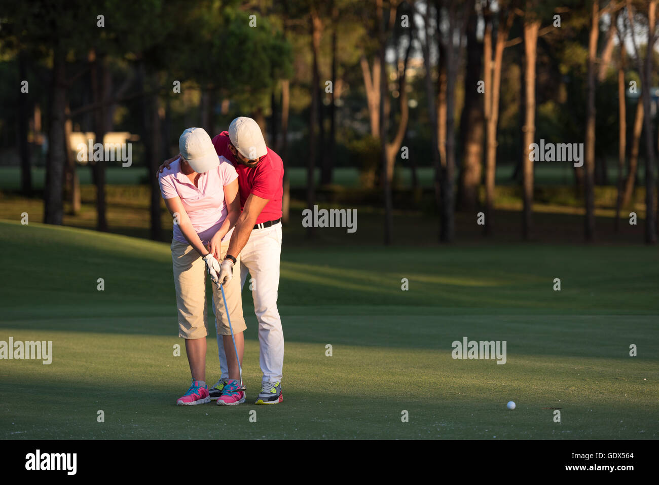 male golf instructor teaching female golf player, personal trainer ...