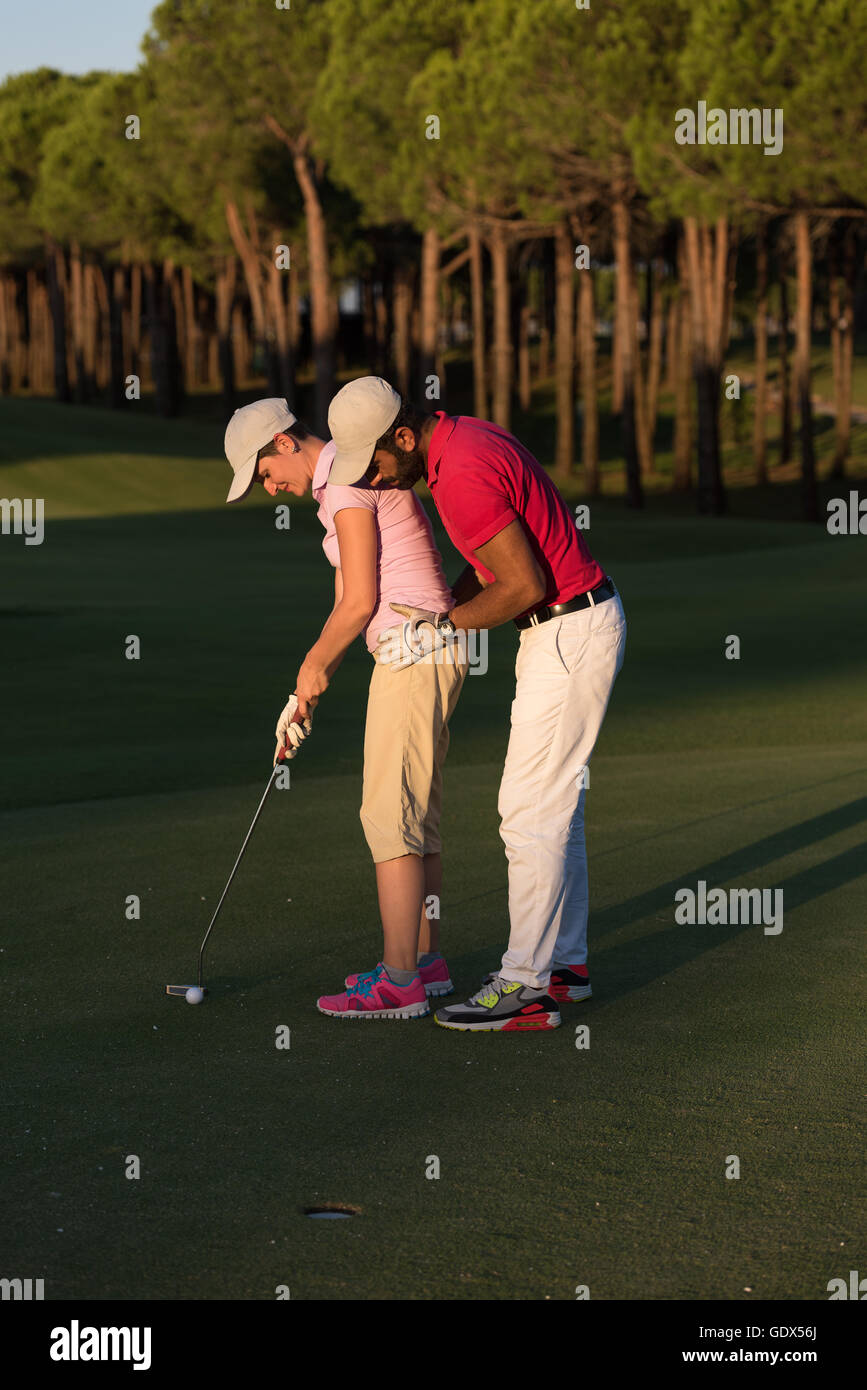 male golf instructor teaching female golf player, personal trainer ...