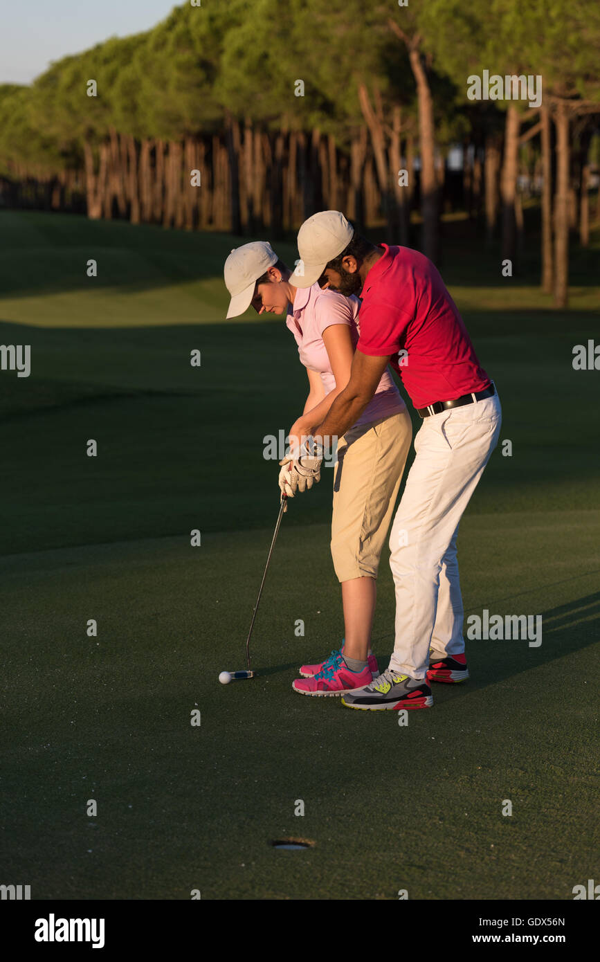 male golf instructor teaching female golf player, personal trainer ...