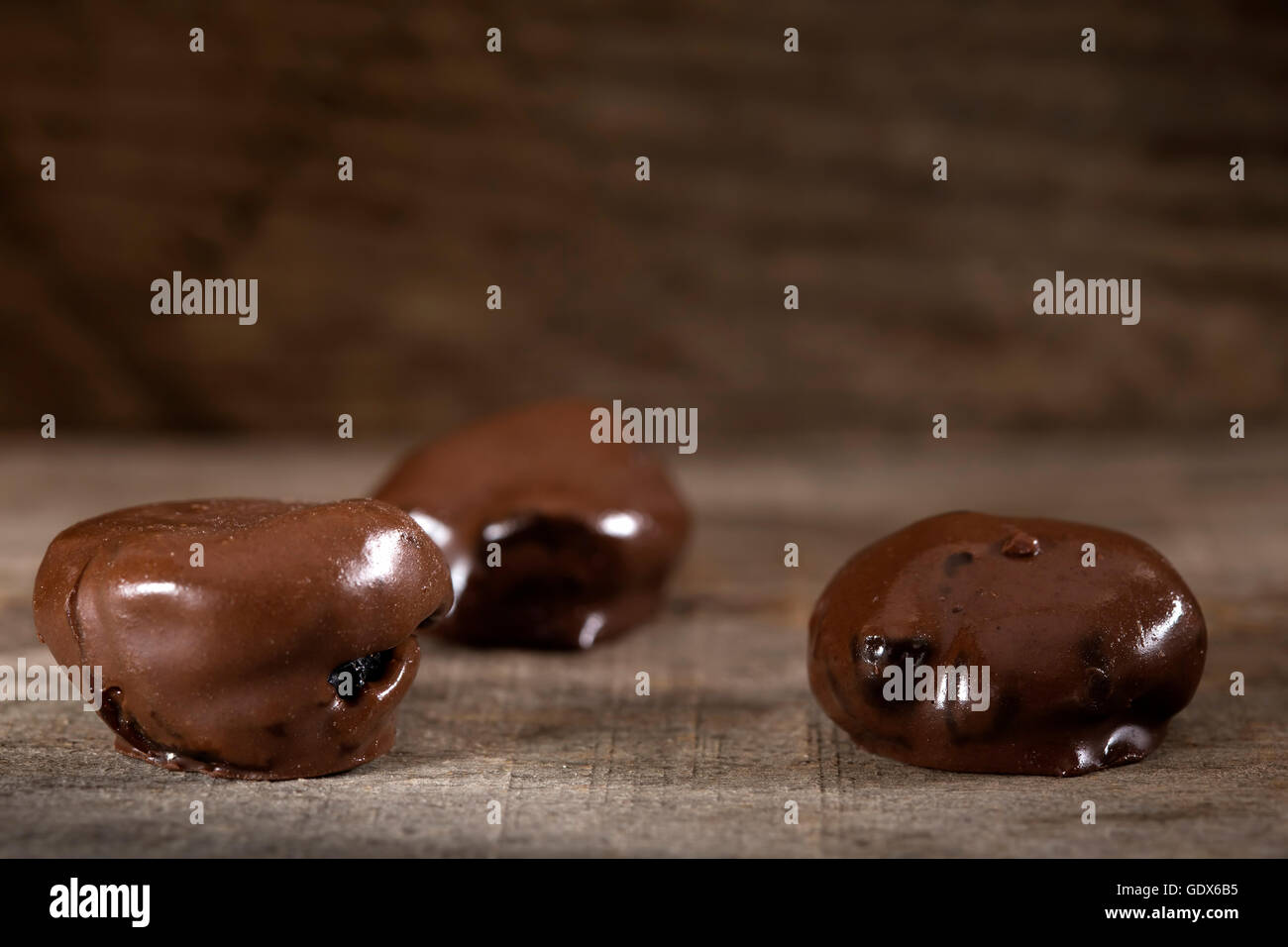 Plums in chocolate on rustic wooden background Stock Photo - Alamy