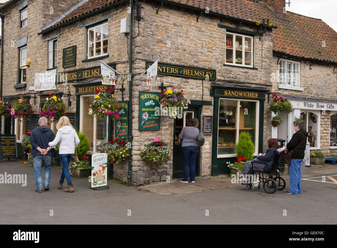 2 people pass while others buy ice creams at Hunters of Helmsley, an ...