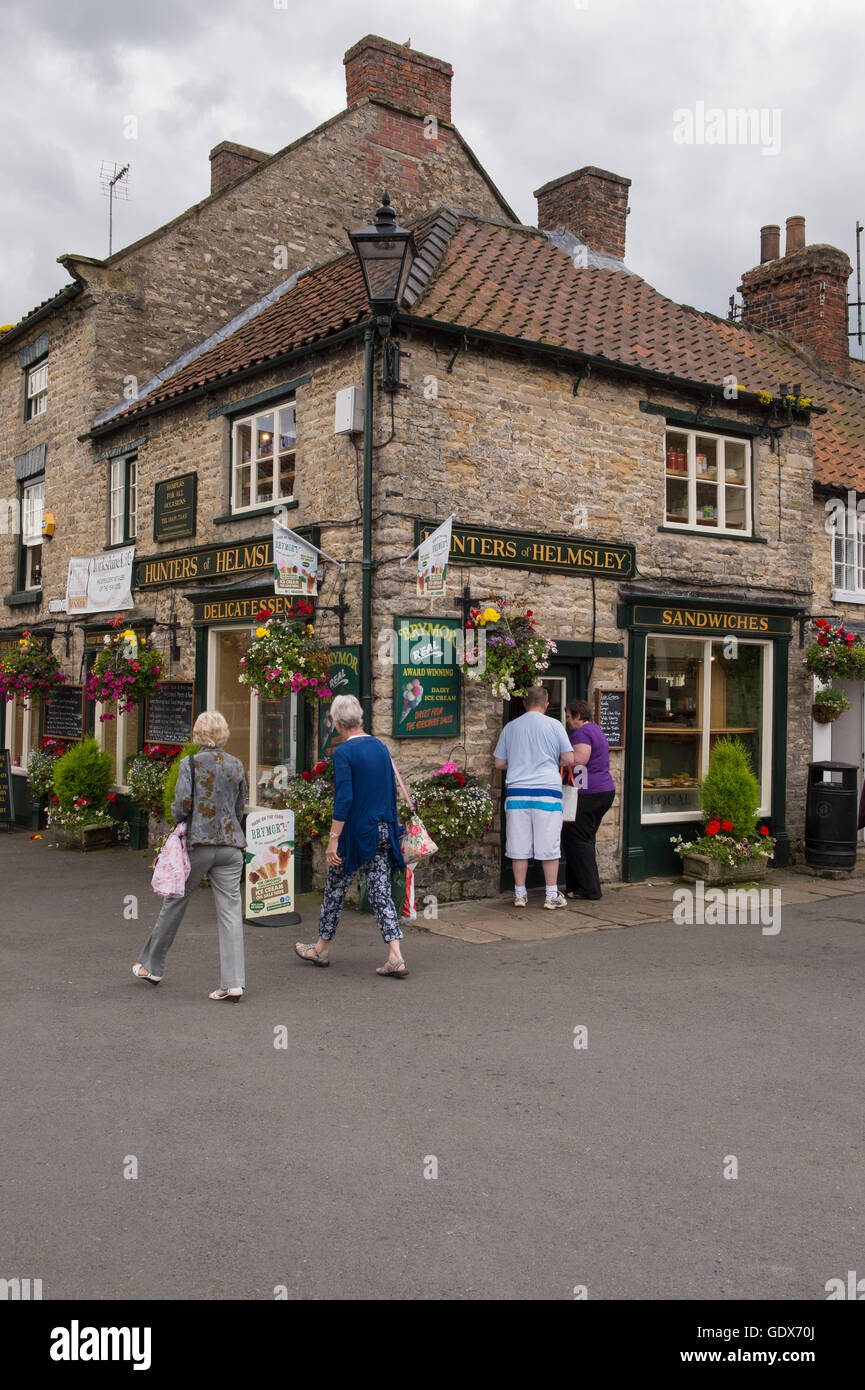 2 people pass while a couple buy ice creams at Hunters of Helmsley, an ...