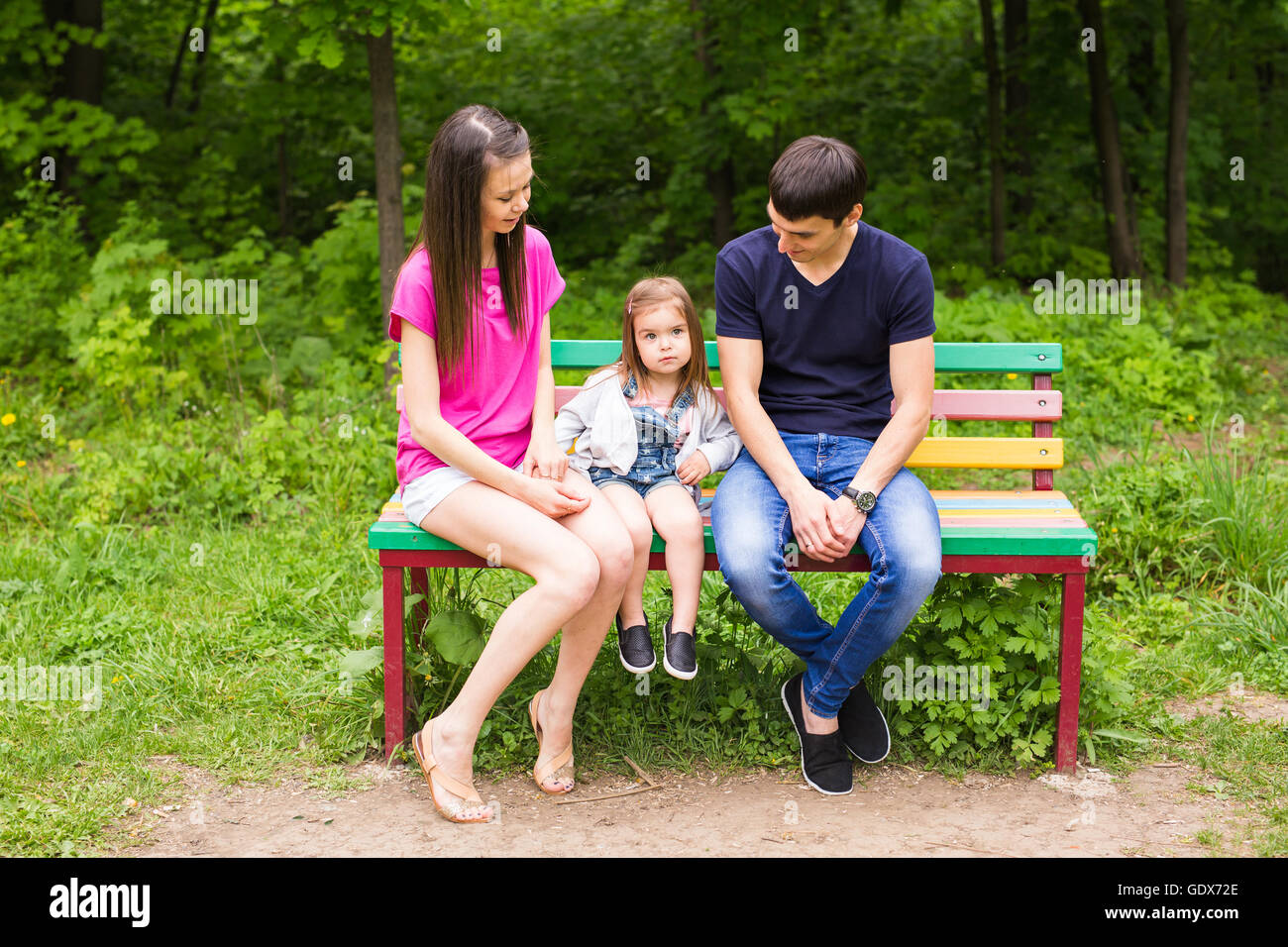 Family sitting on park bench Stock Photo - Alamy