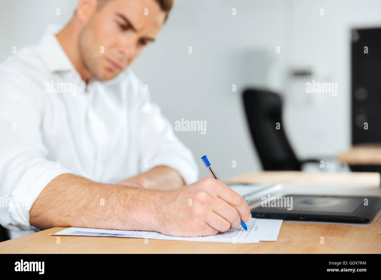 Concentrated young businessman sitting and writing at the table Stock ...