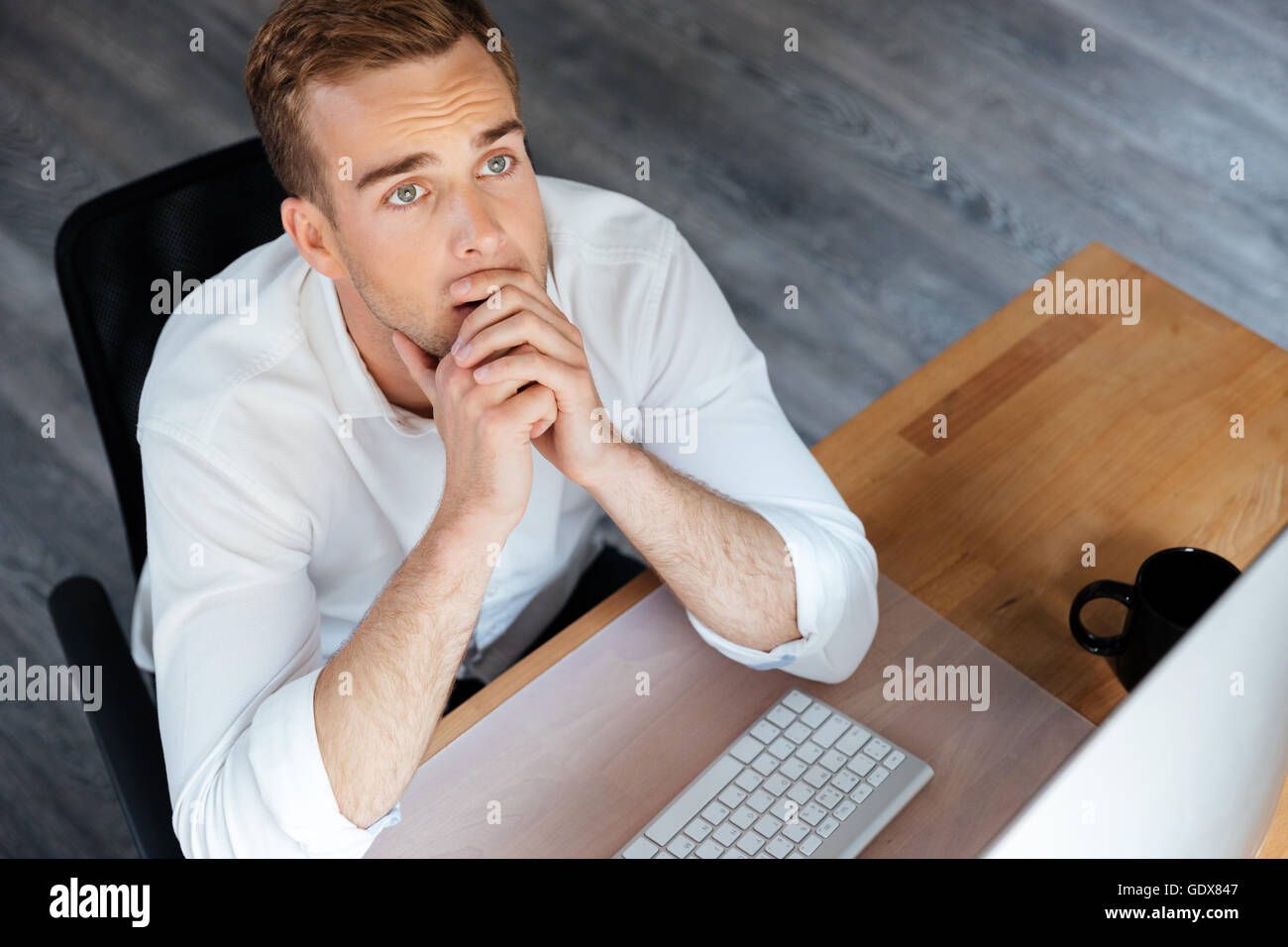 Top view of pensive young businessman working with computer and ...