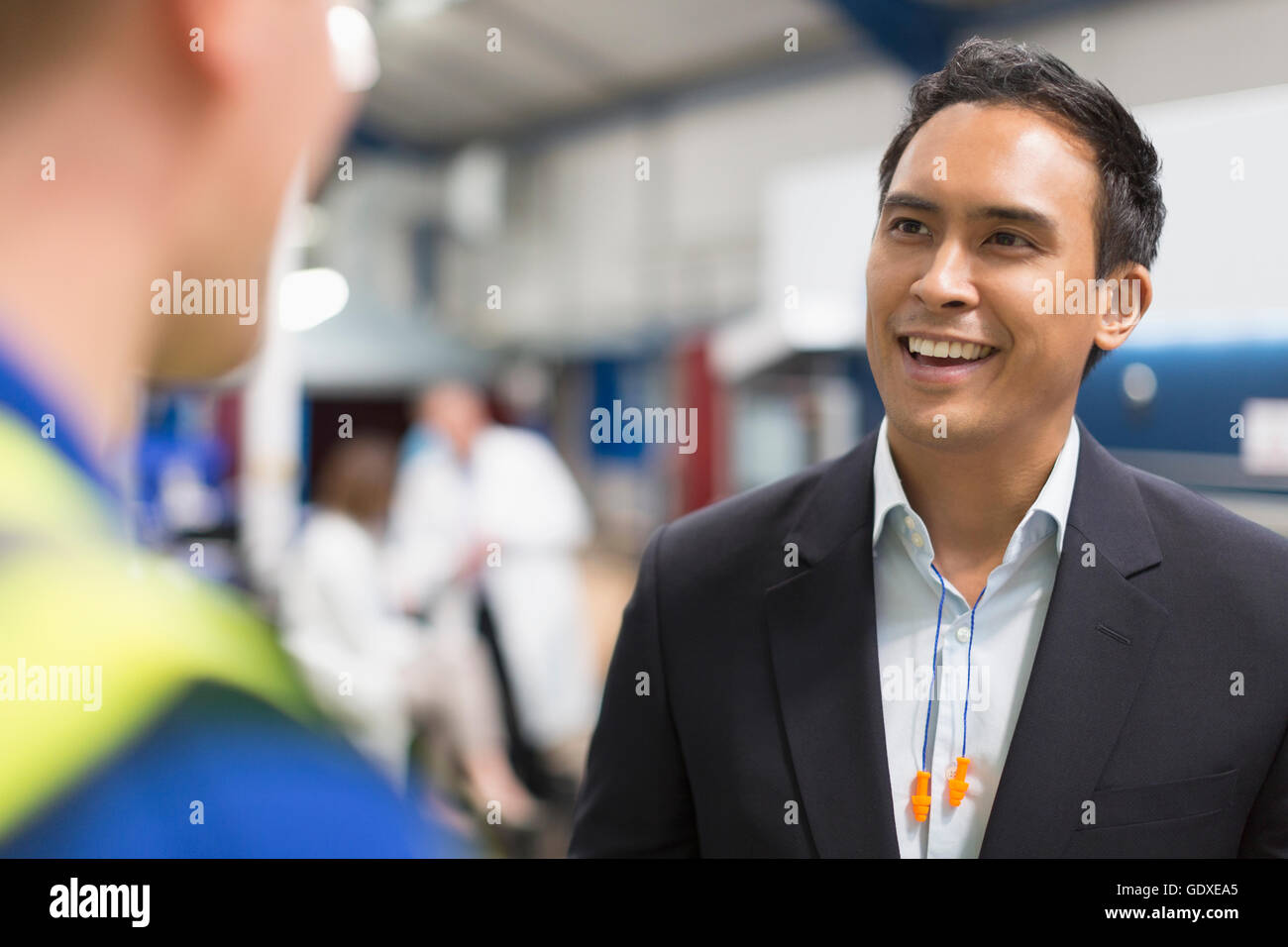 Smiling manager talking with worker in steel factory Stock Photo - Alamy