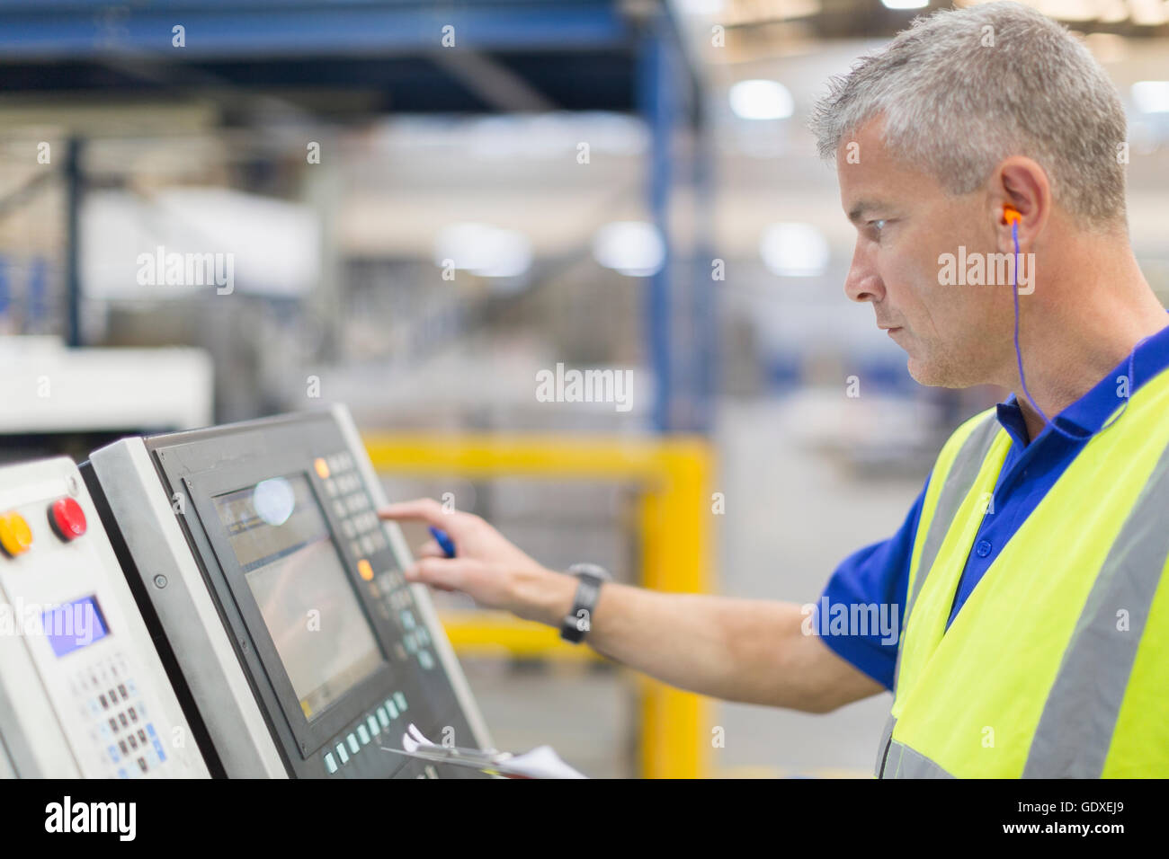 Worker operating machinery at control panel in steel factory Stock ...