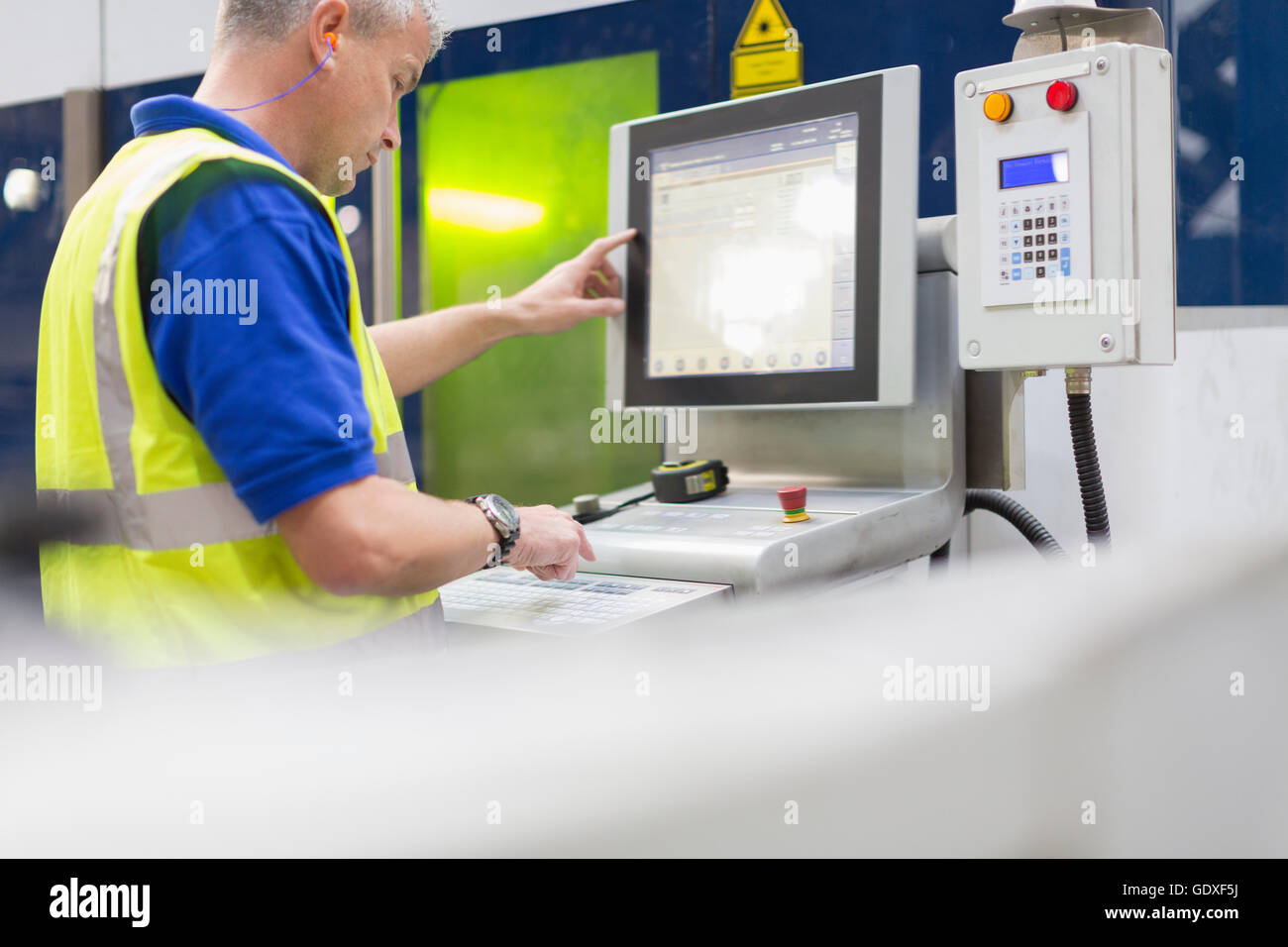 Worker operating machinery at control panel in steel factory Stock ...
