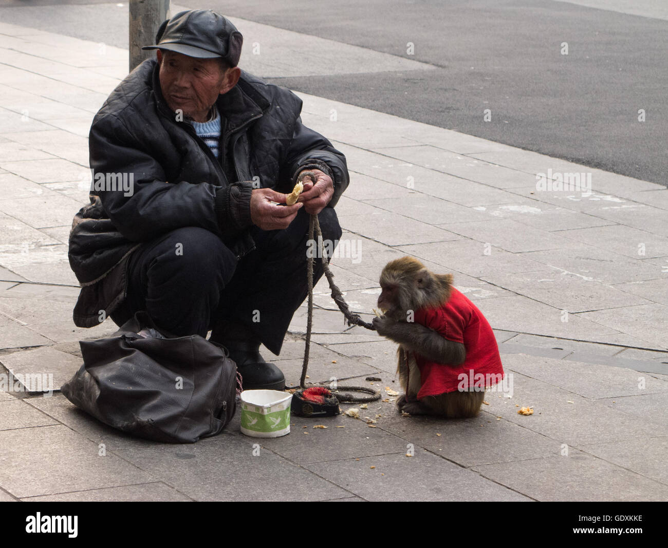 A man carry a monkey to beg on a street Stock Photo - Alamy