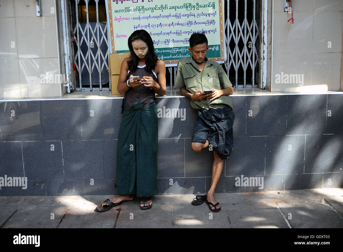2015 two young burmese men are busy using their smartphones hi-res ...
