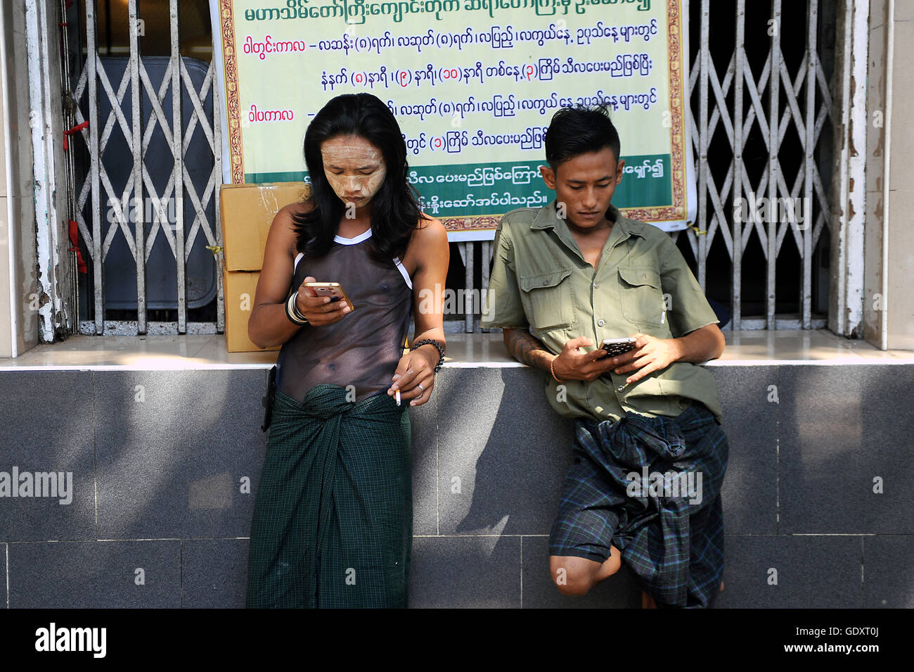 2015 two young burmese men are busy using their smartphones hi-res ...