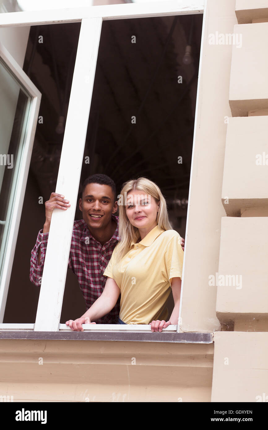 Happy couple looking from window Stock Photo - Alamy