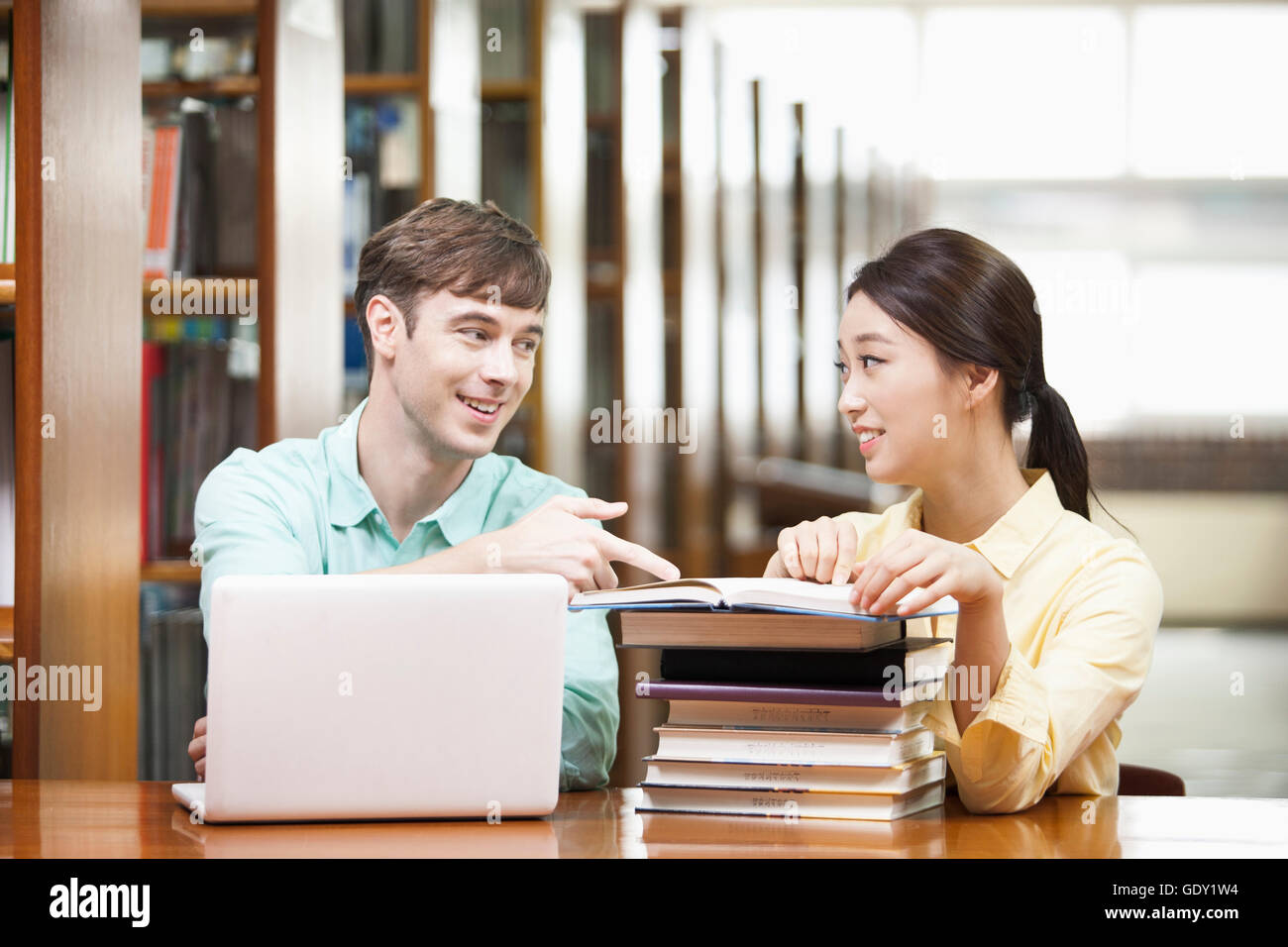 Two college students studying and talking together at library Stock ...
