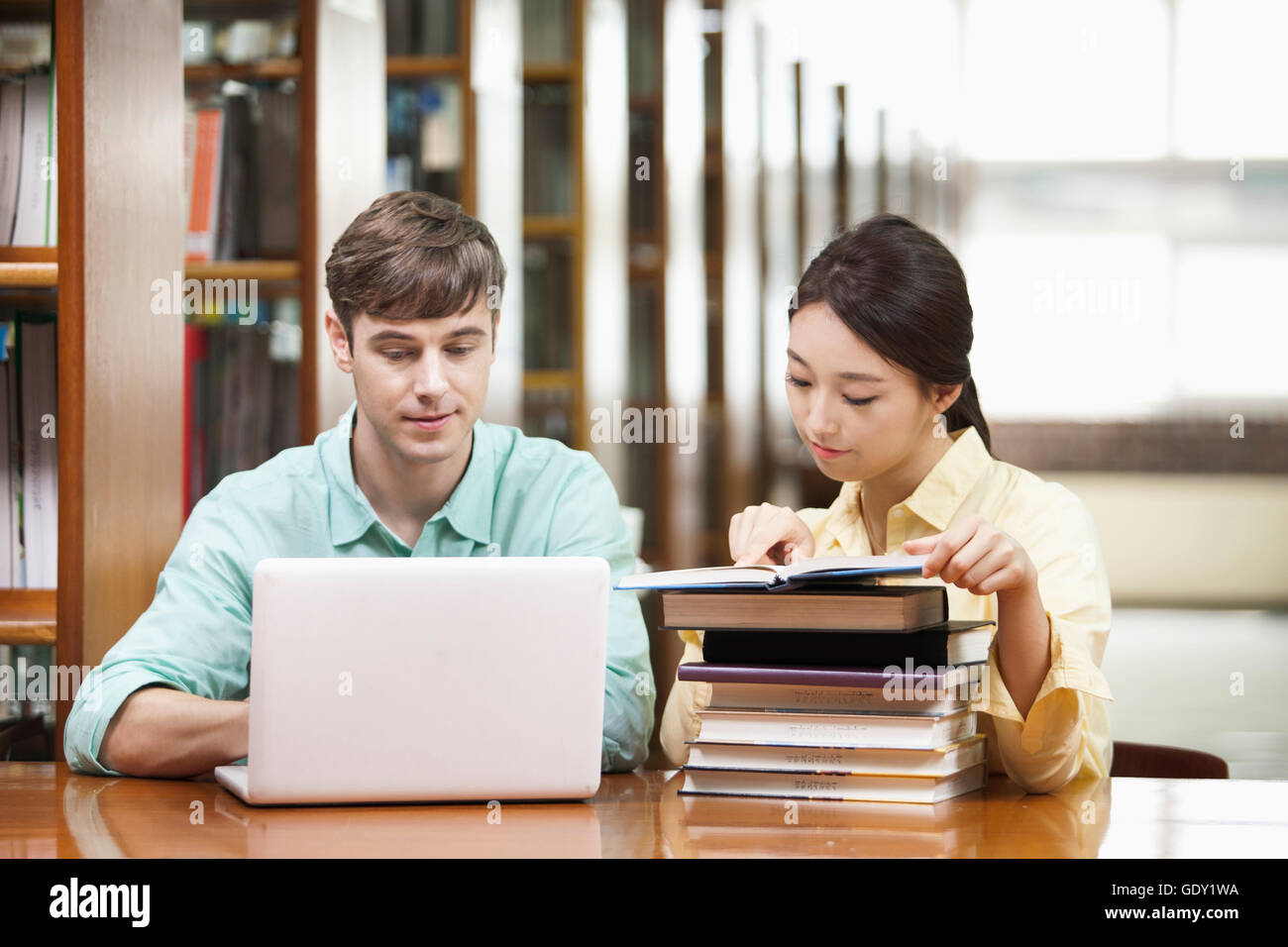 Two college students studying together with notebook computer and books ...