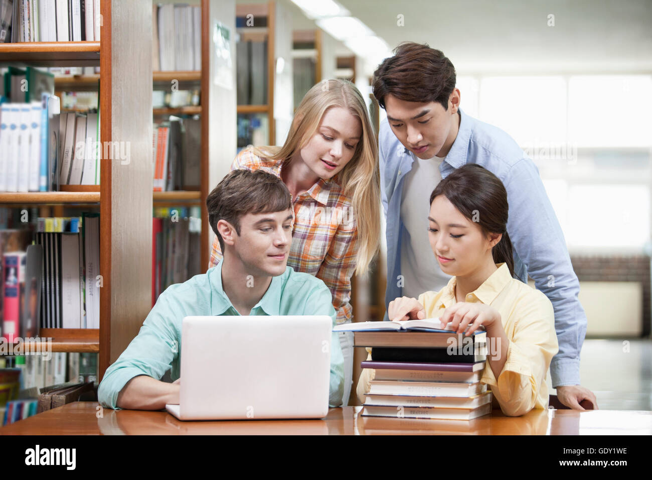 Four college students studying together with notebook computer and ...