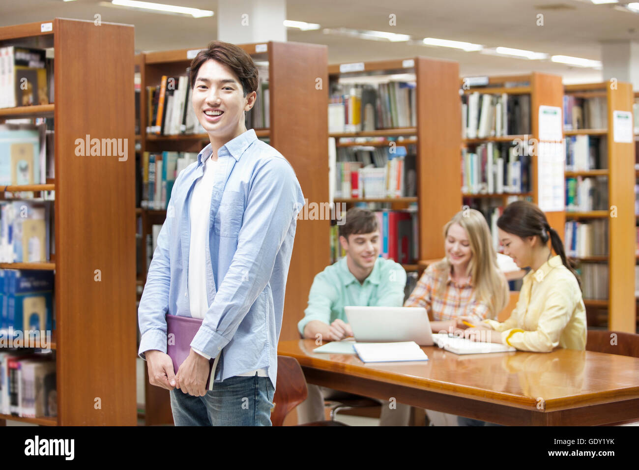 Young smiling male college student standing with three college students ...