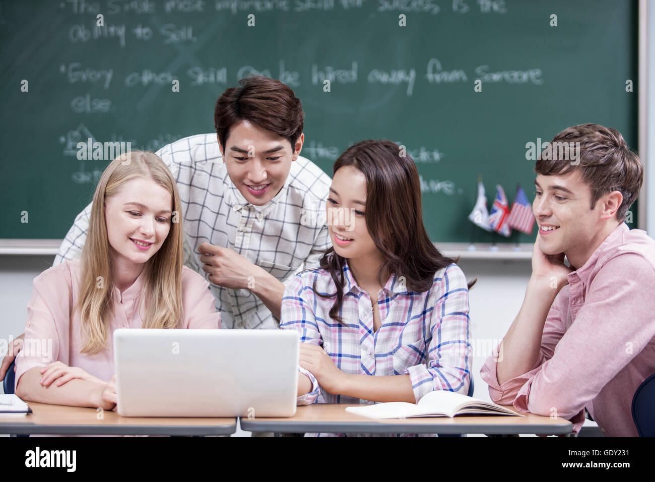 Four college students studying at classroom with a notebook computer ...