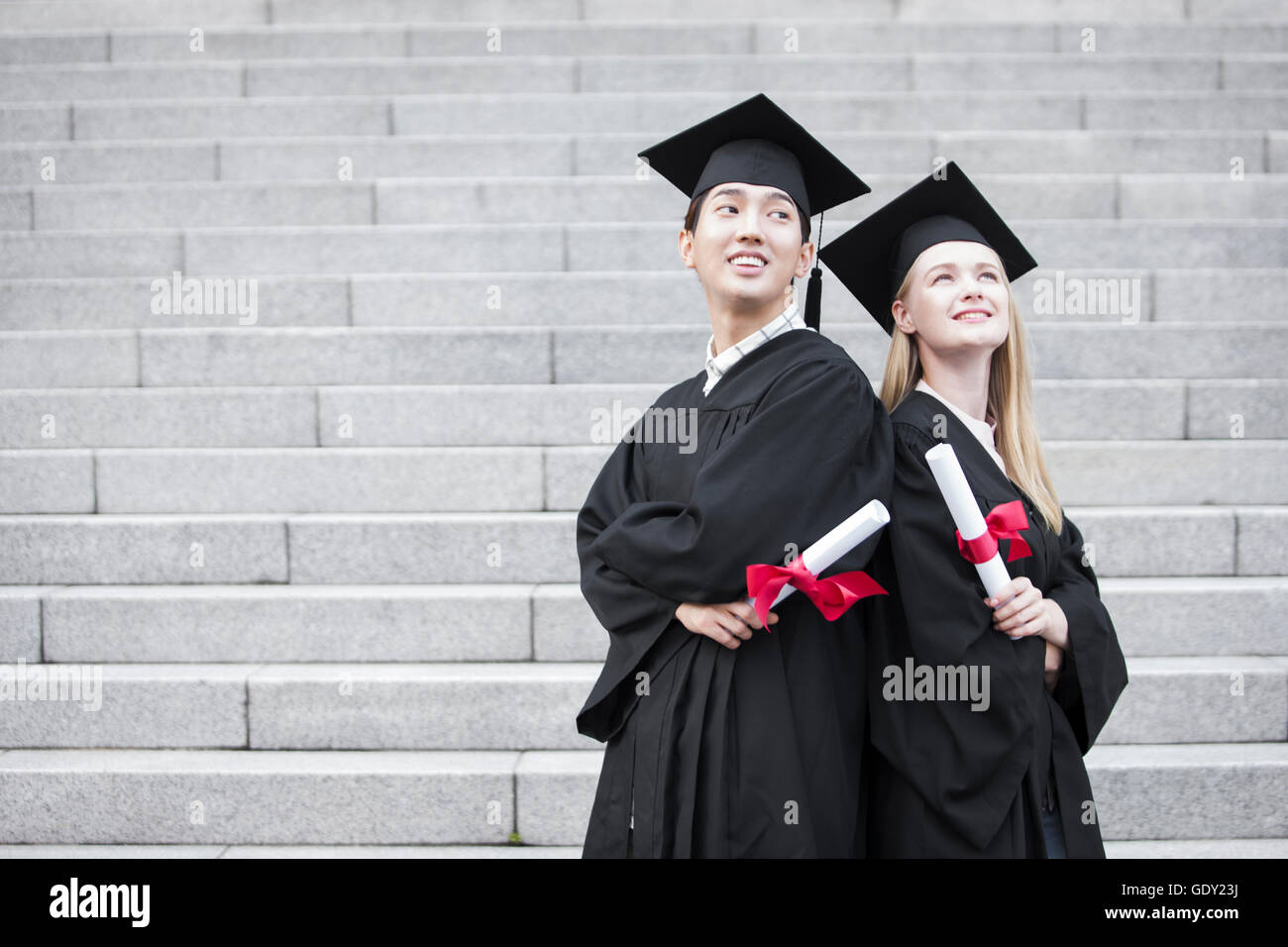 Smiling male college graduate and smiling female college graduate back ...