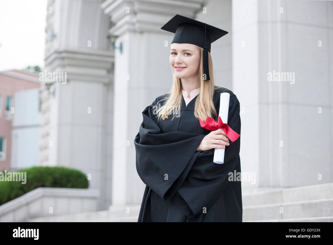 Young smiling female college graduate with her arms folded Stock Photo ...