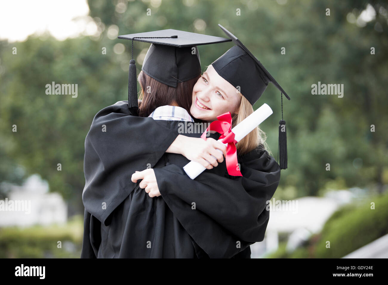 Portrait of two female graduates hugging smiling Stock Photo - Alamy