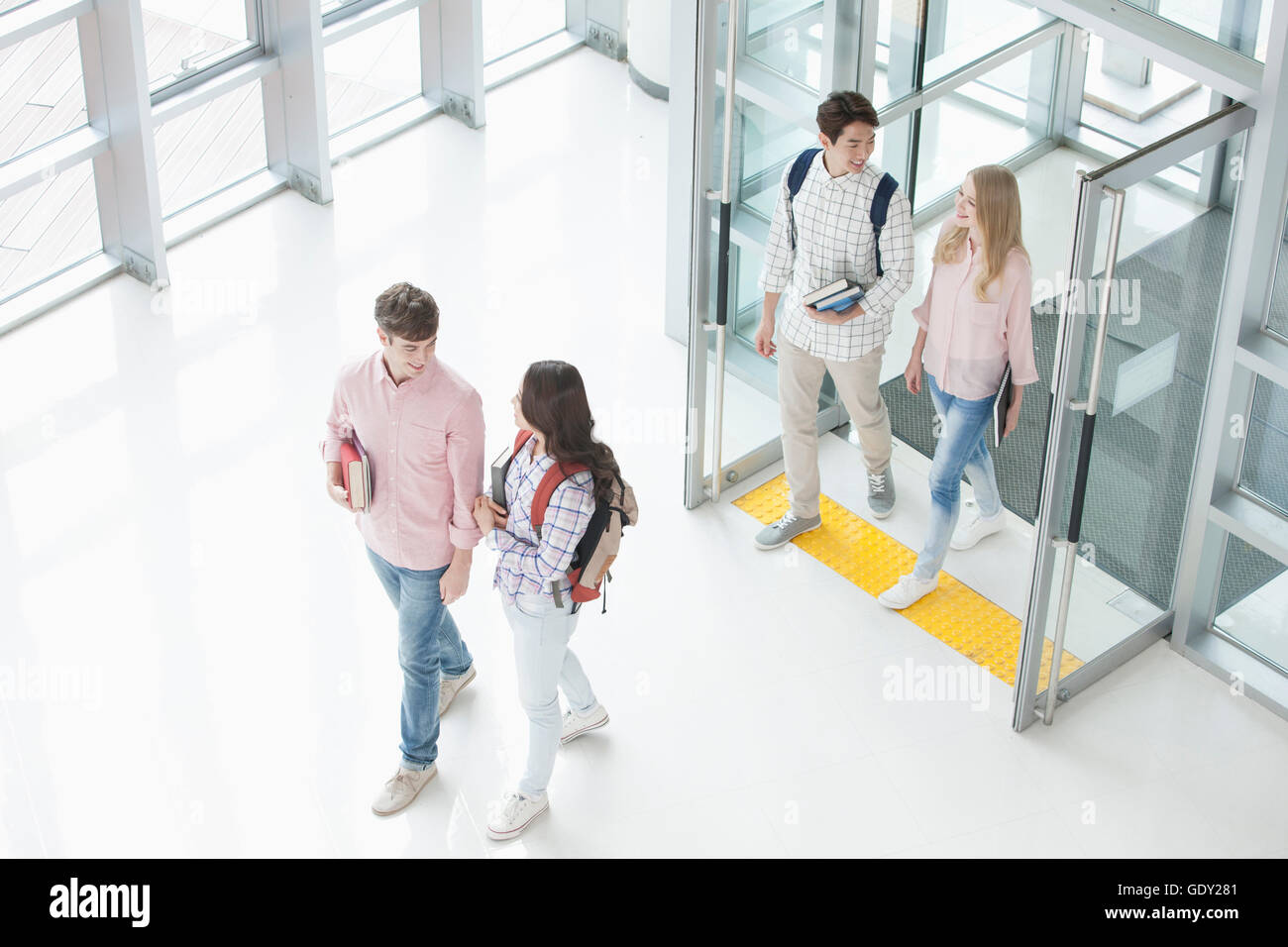 Four global college students walking into a gate Stock Photo - Alamy