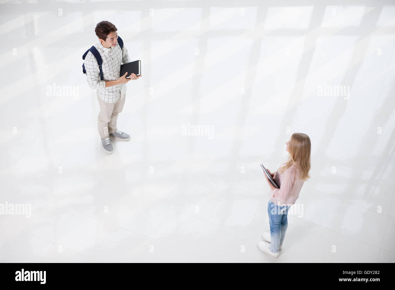 High angle side view of two global college students standing face to ...
